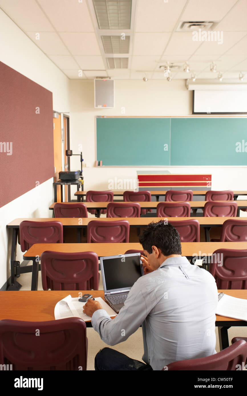 Rear view of a college student sitting in a lecture hall in front of a ...
