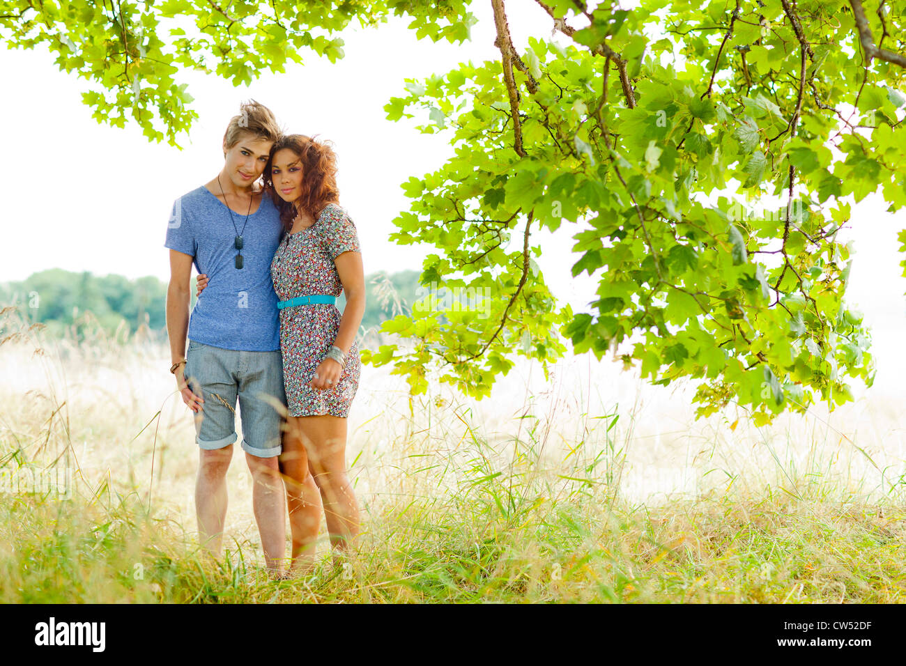 Happy couple standing under tree Stock Photo - Alamy