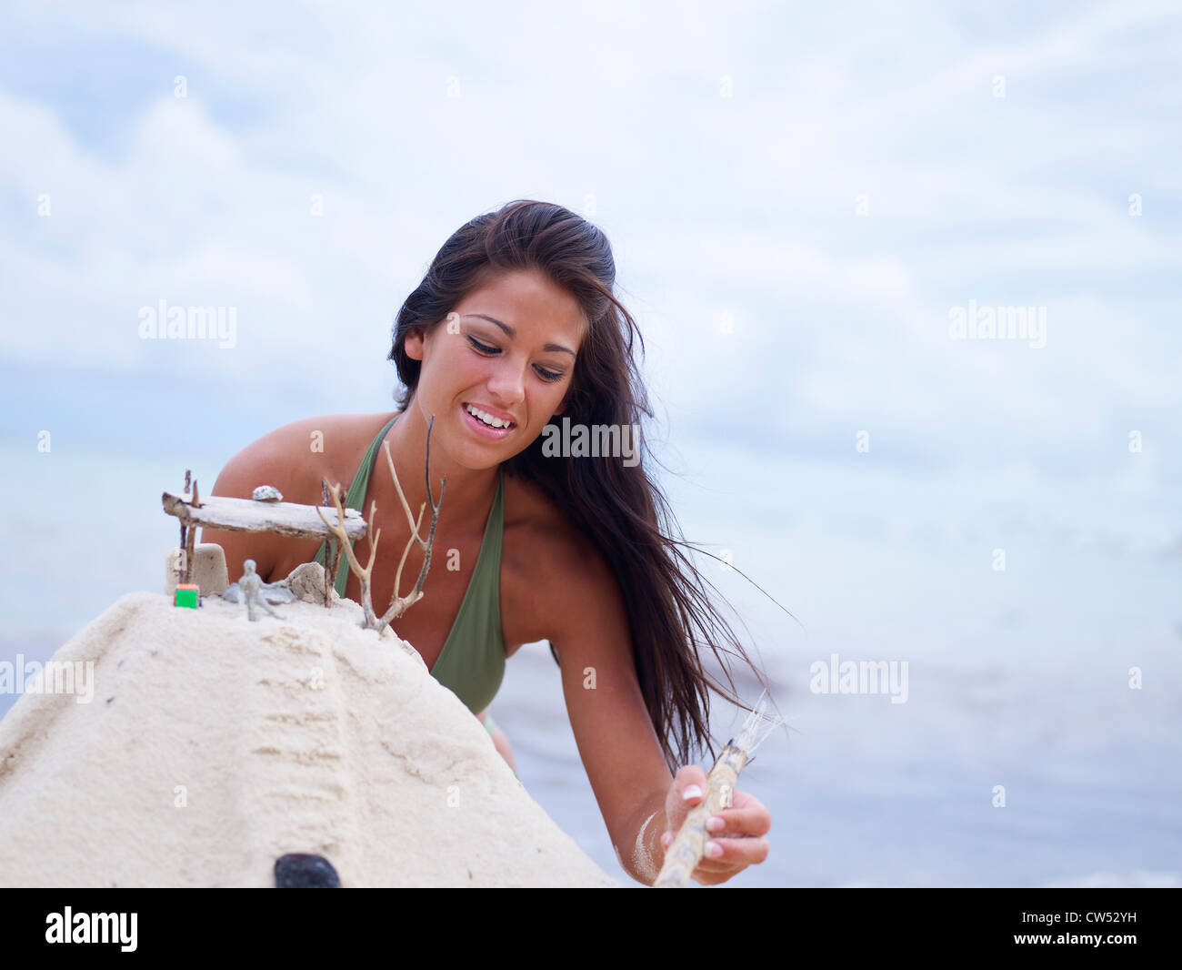 Mexico, Quintana Roo, Tulum, Young woman making sand castle on beach ...