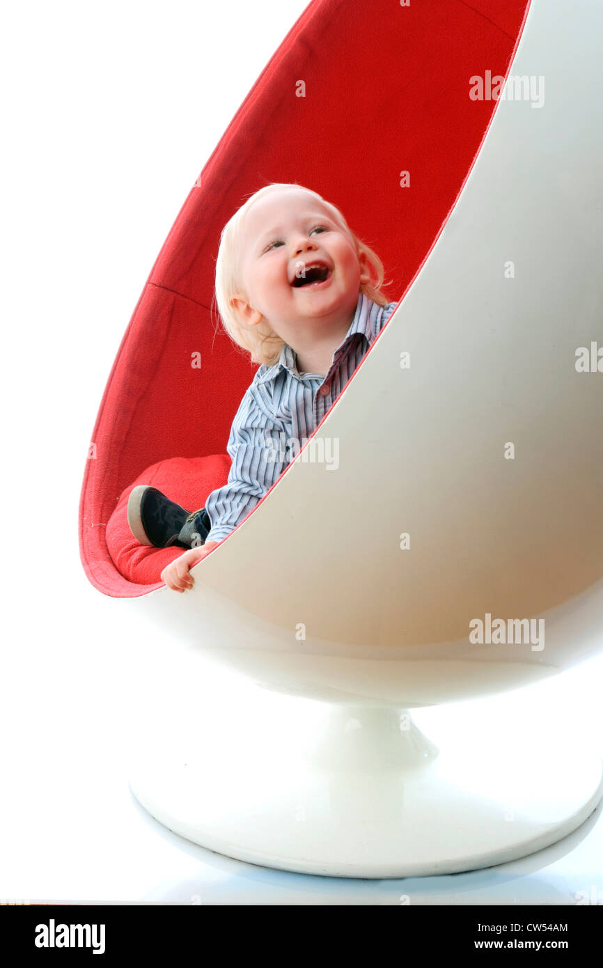 Studio shot of boy seating in red and white chair Stock Photo - Alamy