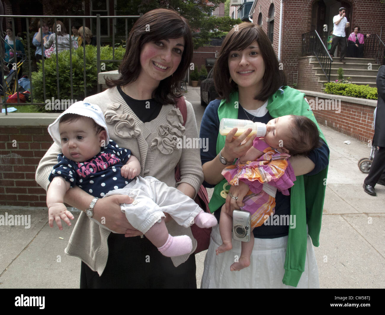 Two young, religious Jewish women pose for a portrait with their babies ...