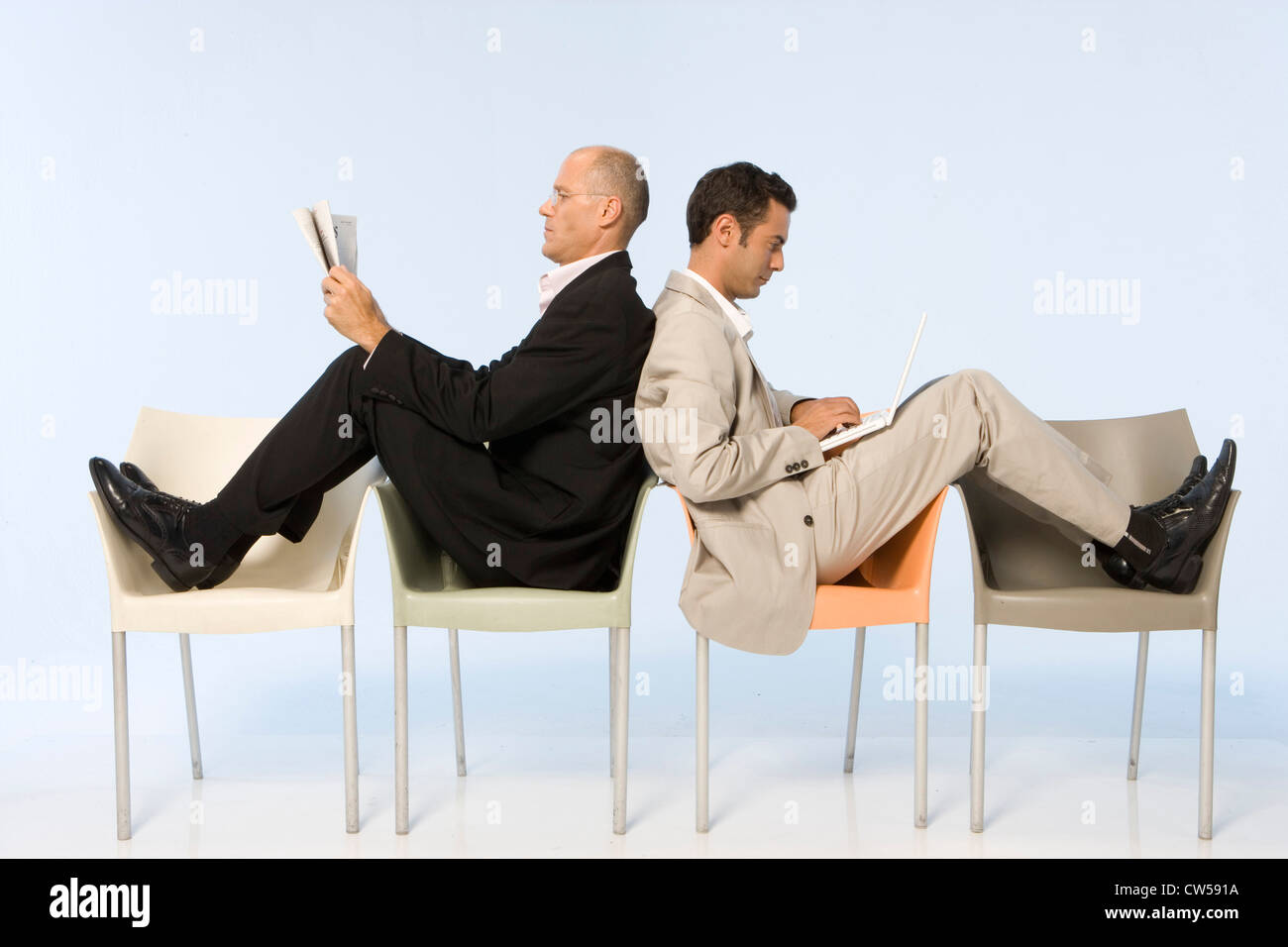 Two businessmen sitting back to back in chairs Stock Photo - Alamy