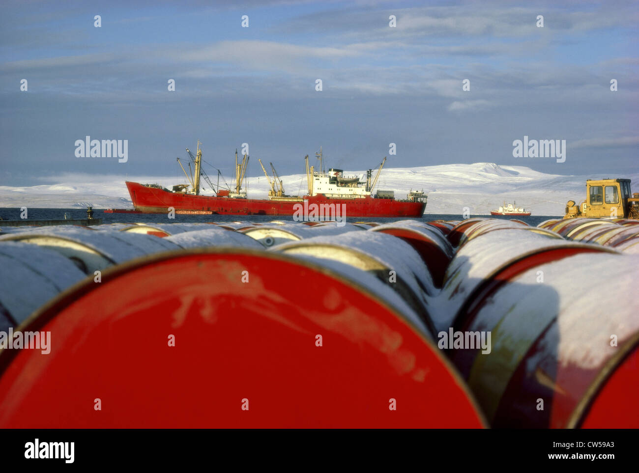Barrels at a commercial dock with a container ship in the background ...