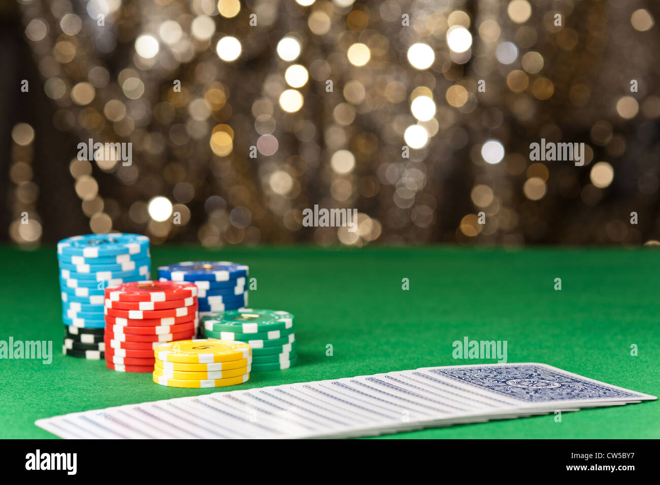 Colorful poker chips and cards in front of a gold glitter background ...