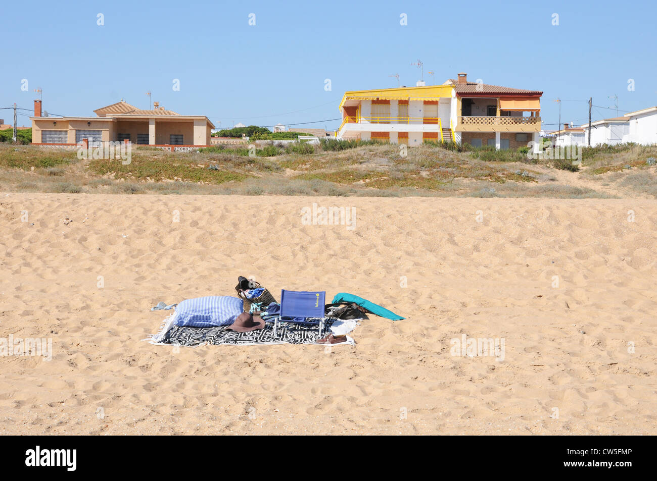 Towels, clothes, various items in pile on golden sandy beach, in front ...
