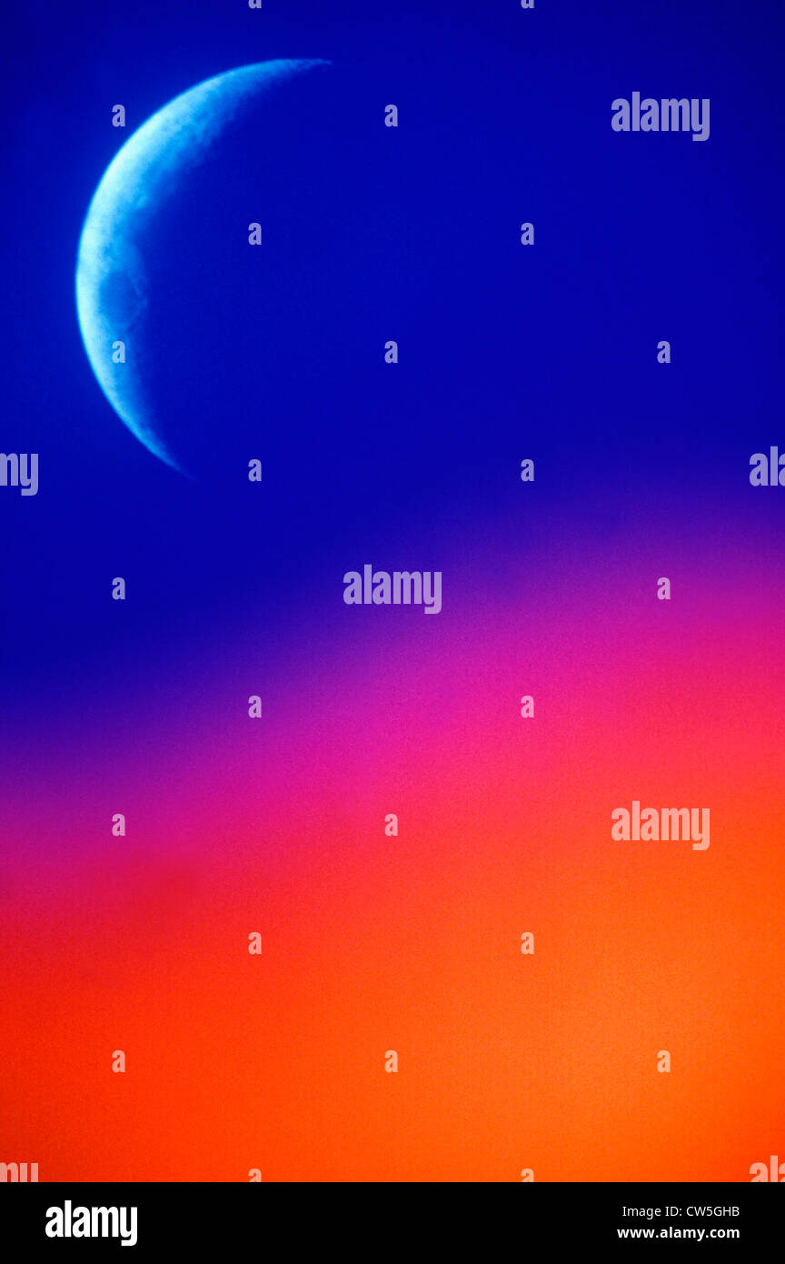 A crescent moon against a sky fading from blue to orange Stock Photo ...