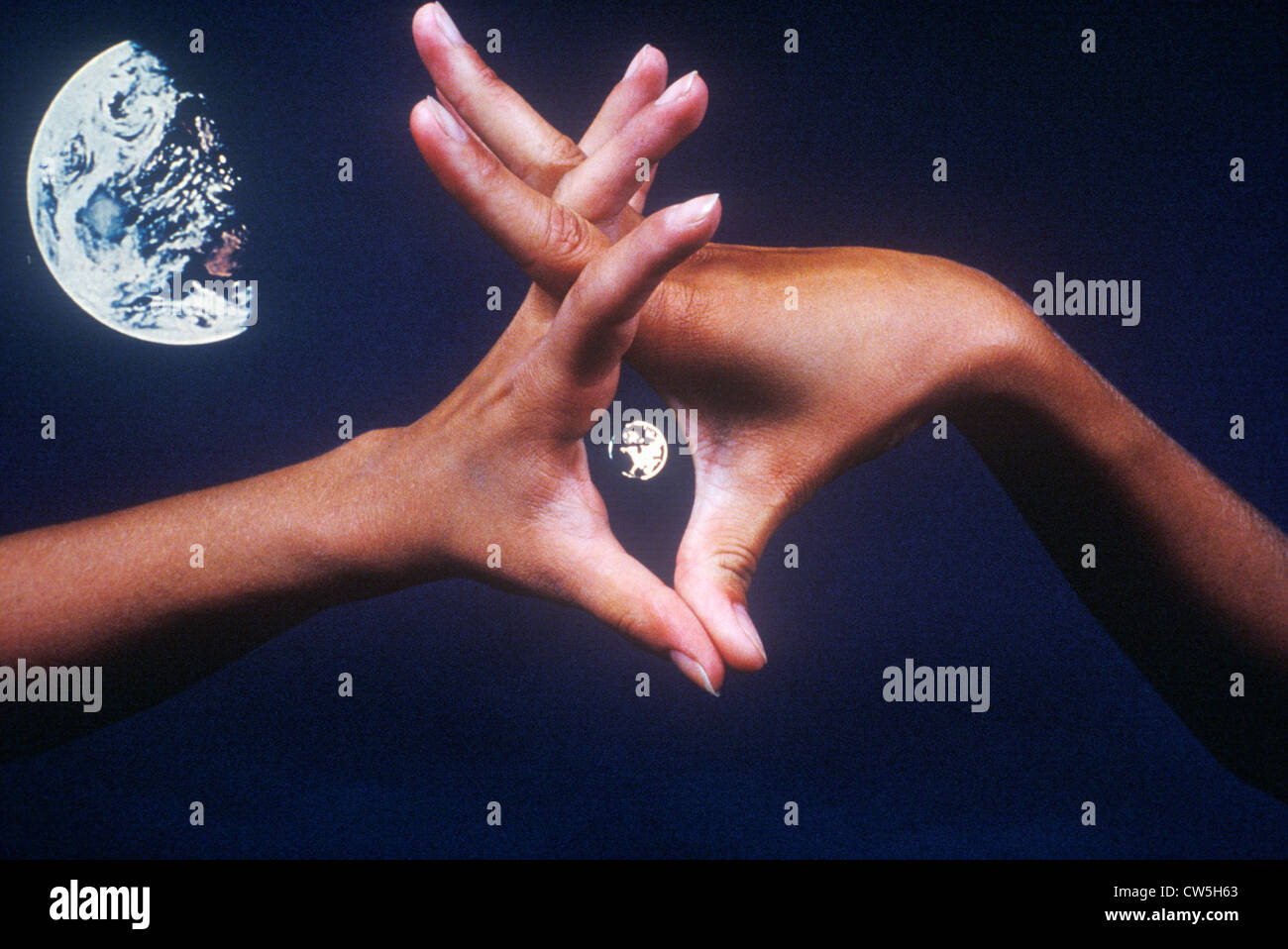 Special effects composite of interlaced hands and Earth in black sky ...