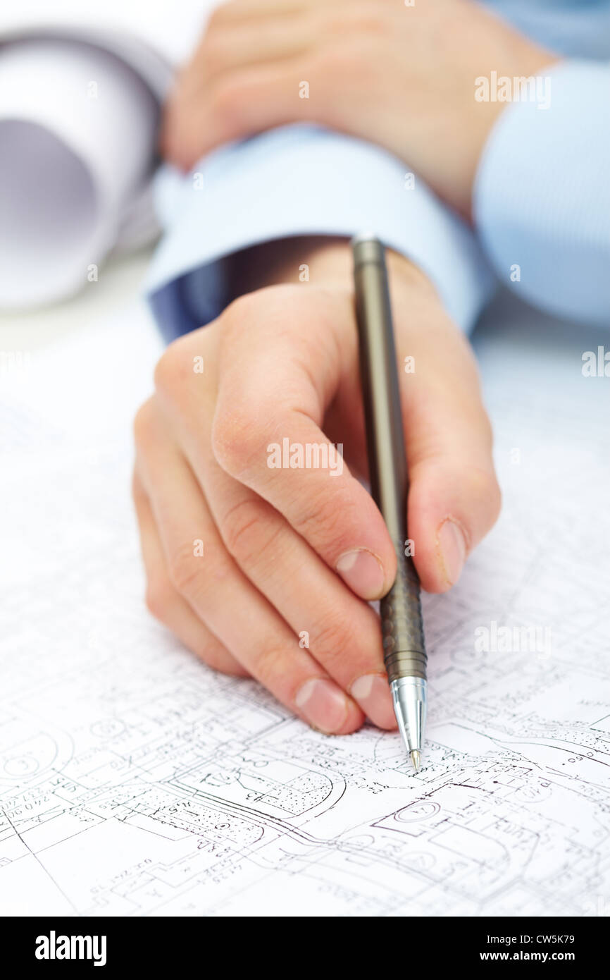 Close-up of engineer hand with pen over blueprint with sketches of ...