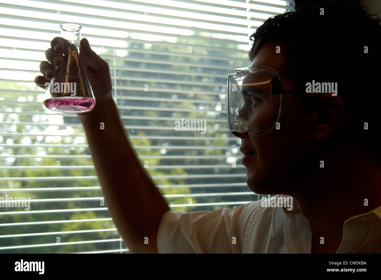 College student holding examining a solution in a conical flask in the ...