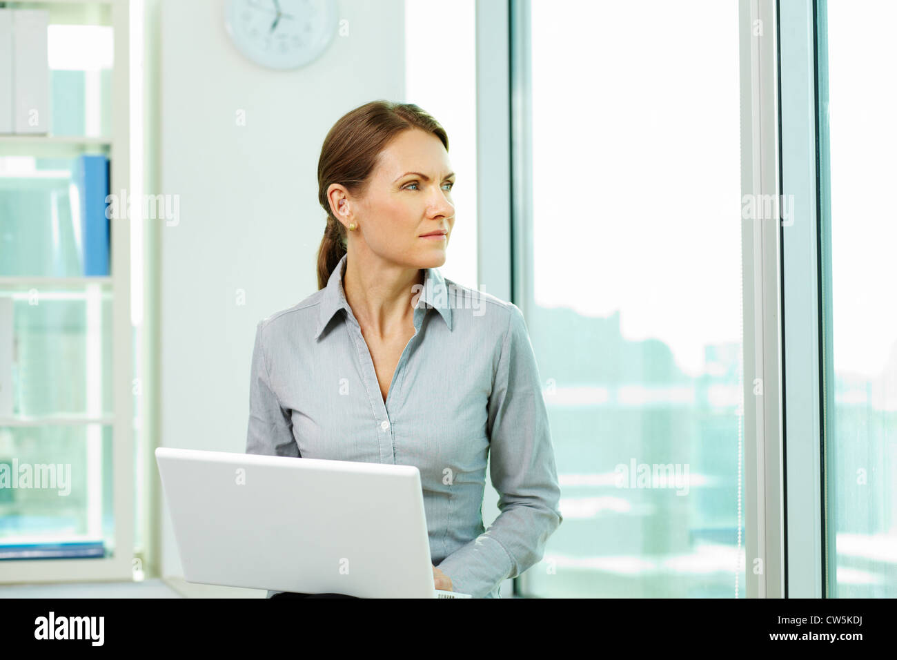 Business lady with laptop looking outside the window, searching for ...