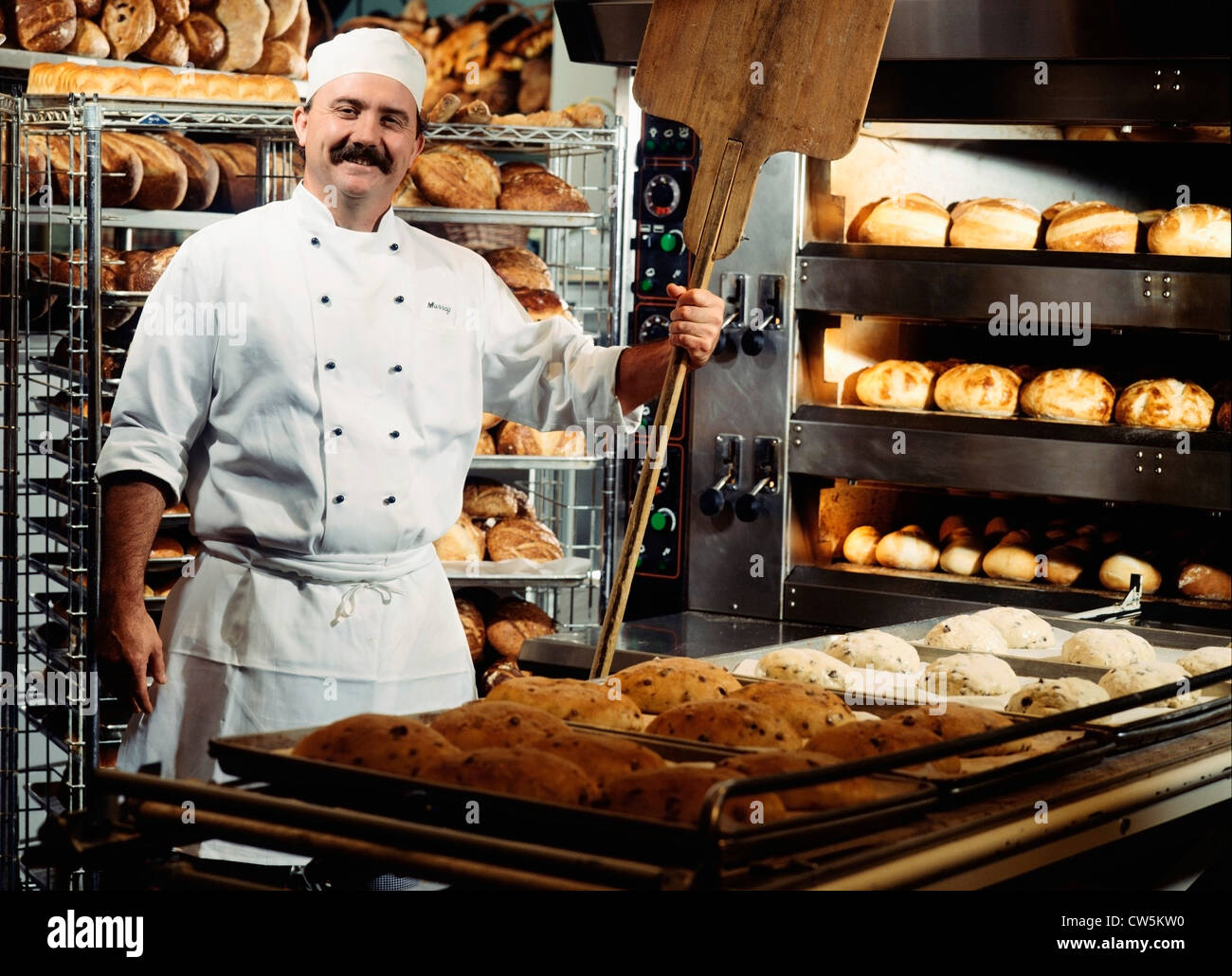 Portrait of a baker standing in a kitchen with breads Stock Photo - Alamy