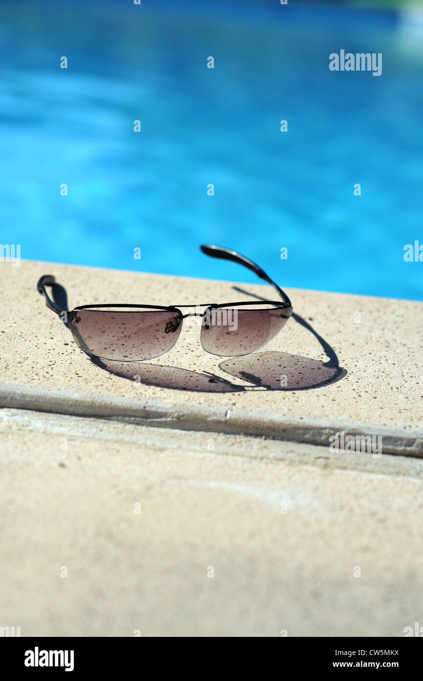 Sunglasses by an outdoor swimming pool in hot sunshine Stock Photo - Alamy