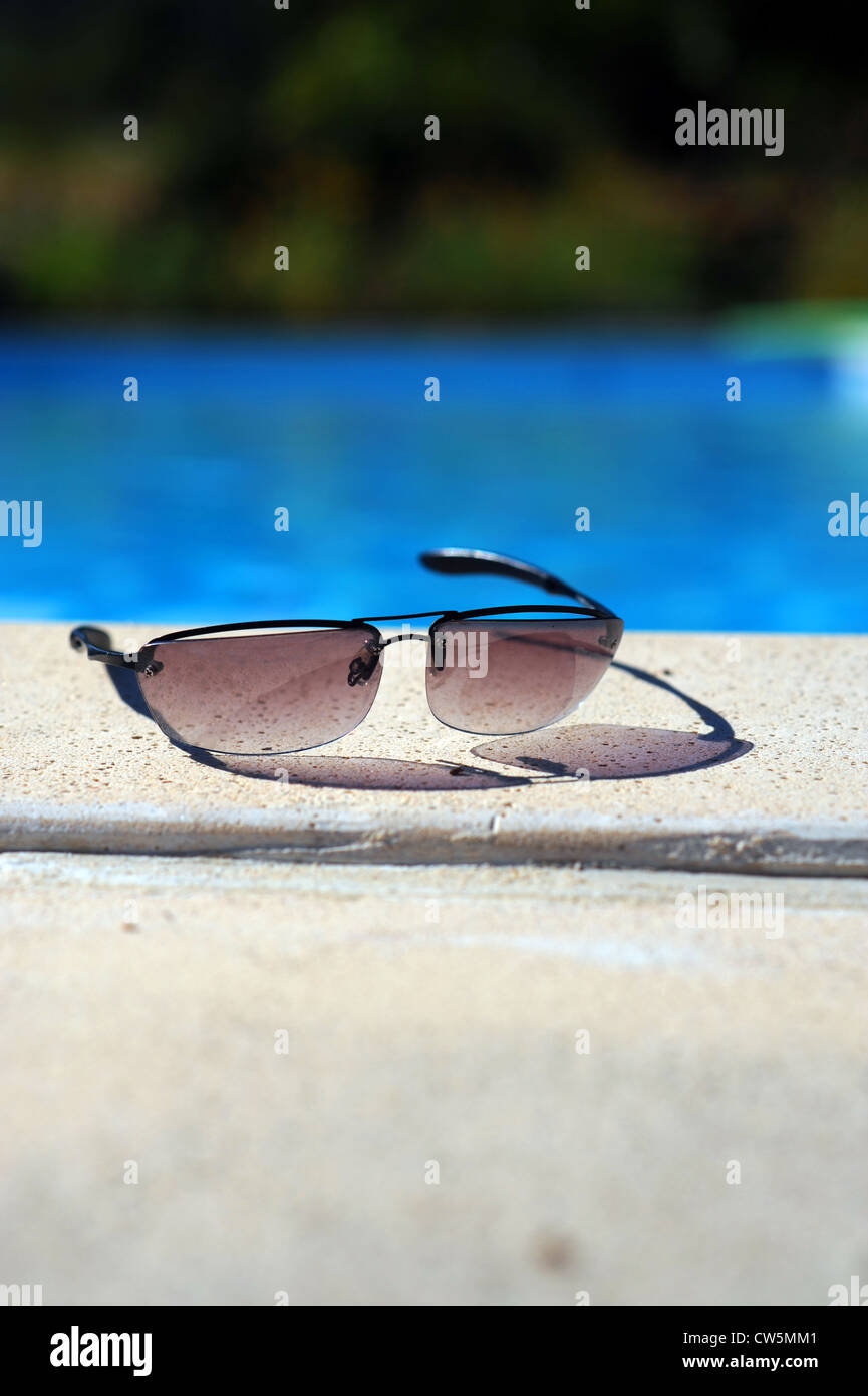 Sunglasses by an outdoor swimming pool in hot sunshine Stock Photo - Alamy