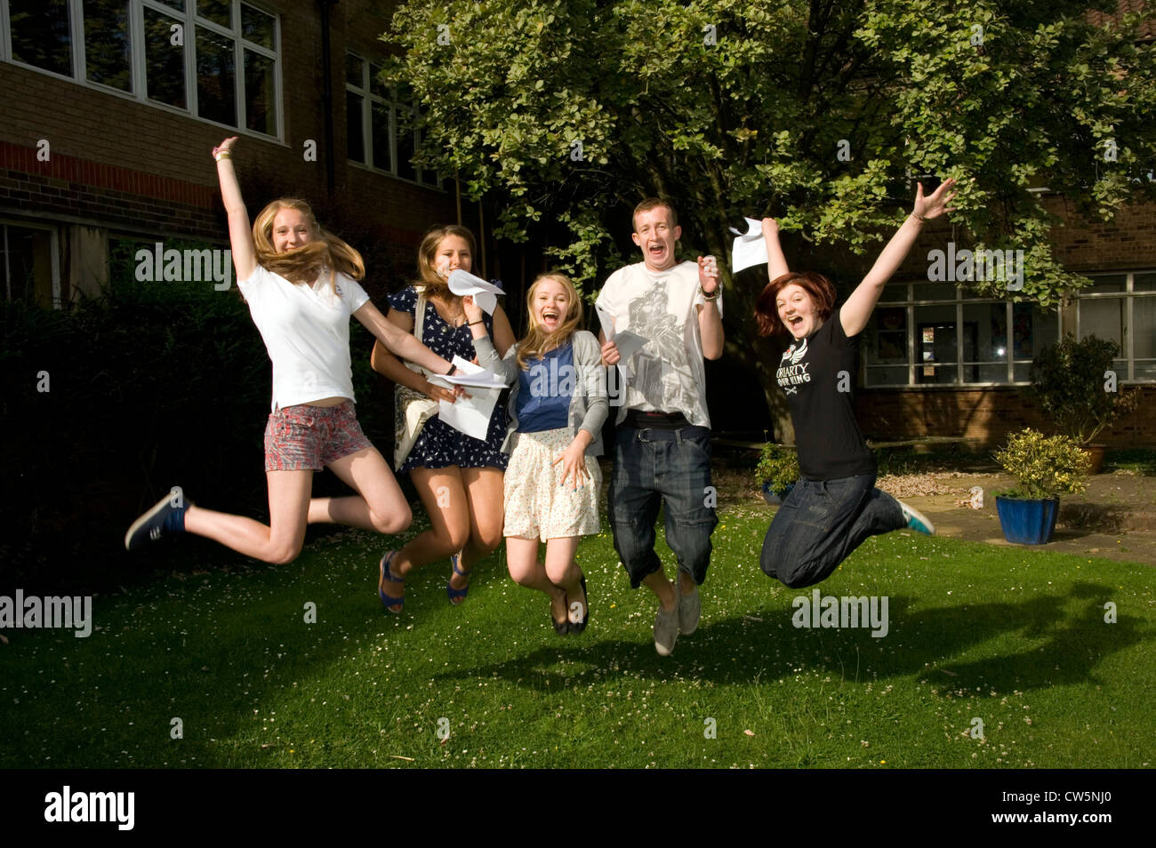 Happy students holding their successful GCSE exam results to camera at ...