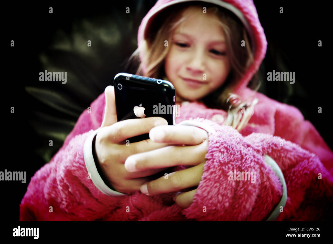 A young girl in a pink hoody looking at a Apple iPhone Stock Photo - Alamy
