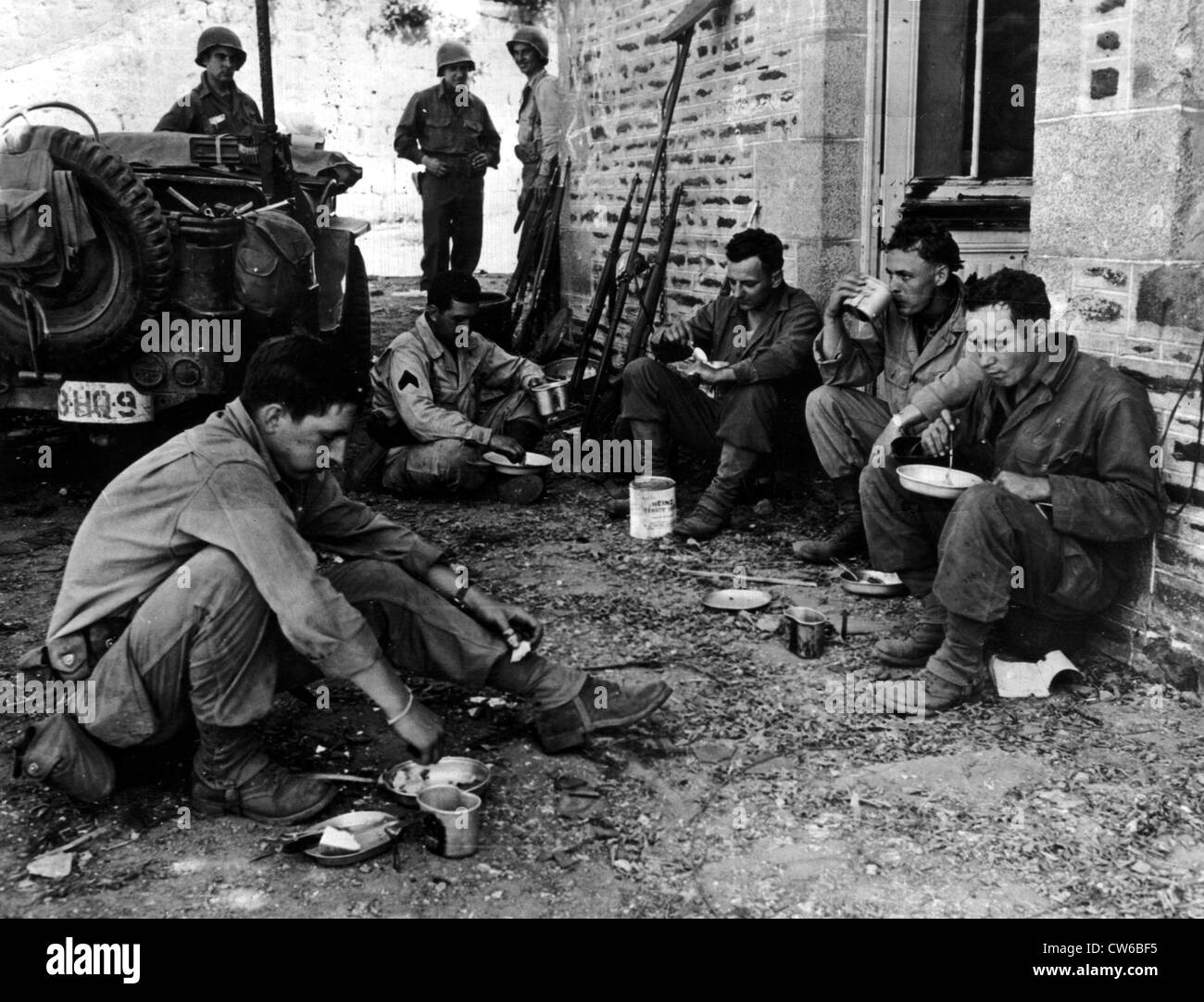 US soldiers eat hot meal in a street of Perriers (France) summer 1944 ...