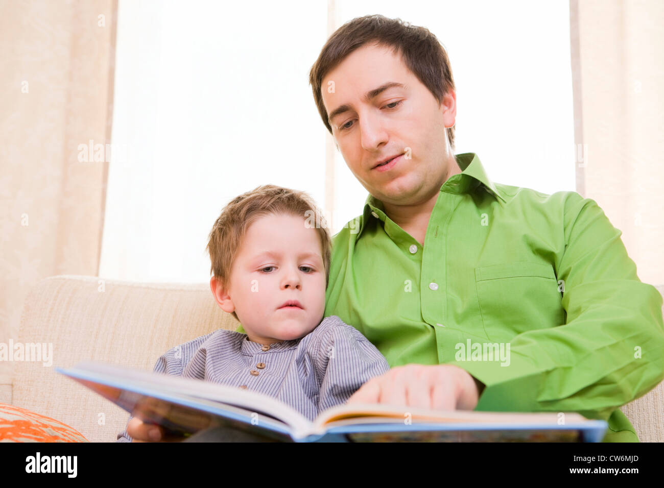 Father and son reading book together at home Stock Photo - Alamy