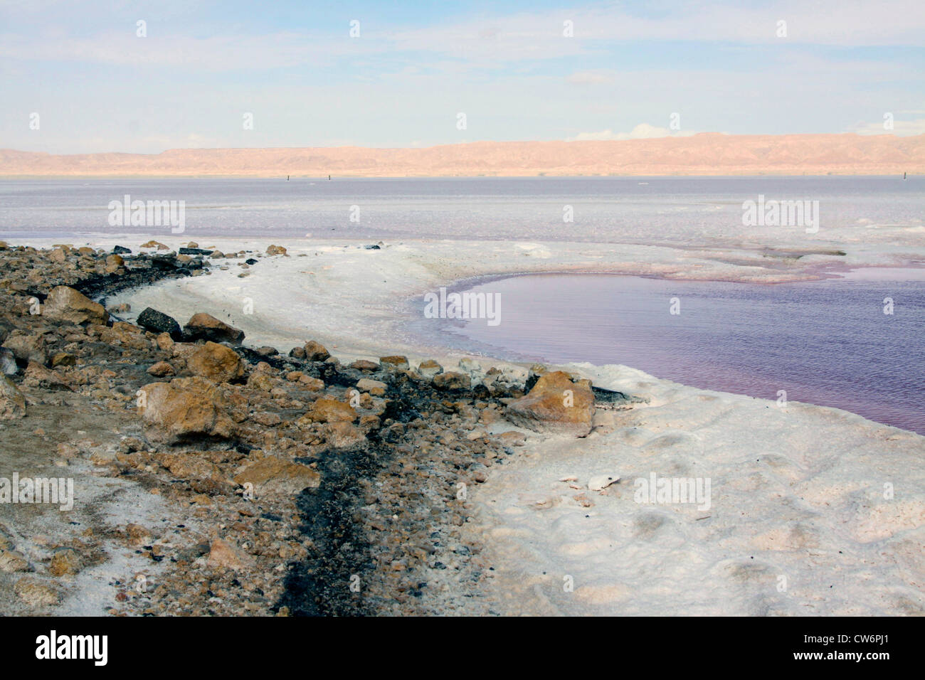 salt lake in Chott el-J rid with red water and road crossing the lake ...
