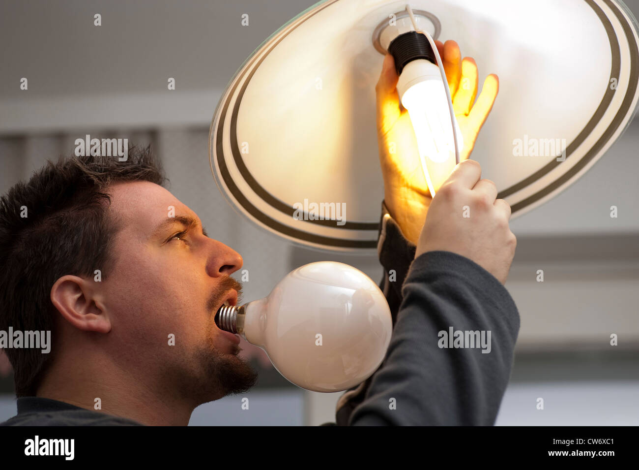 young man changes light bulb Stock Photo - Alamy