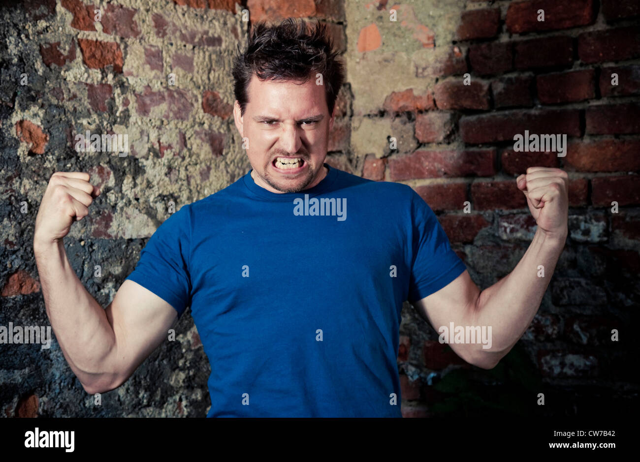 strong, young man in front of y brick wall Stock Photo - Alamy