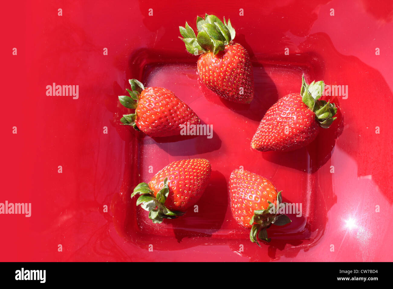Five strawberries in a red bowl Stock Photo - Alamy