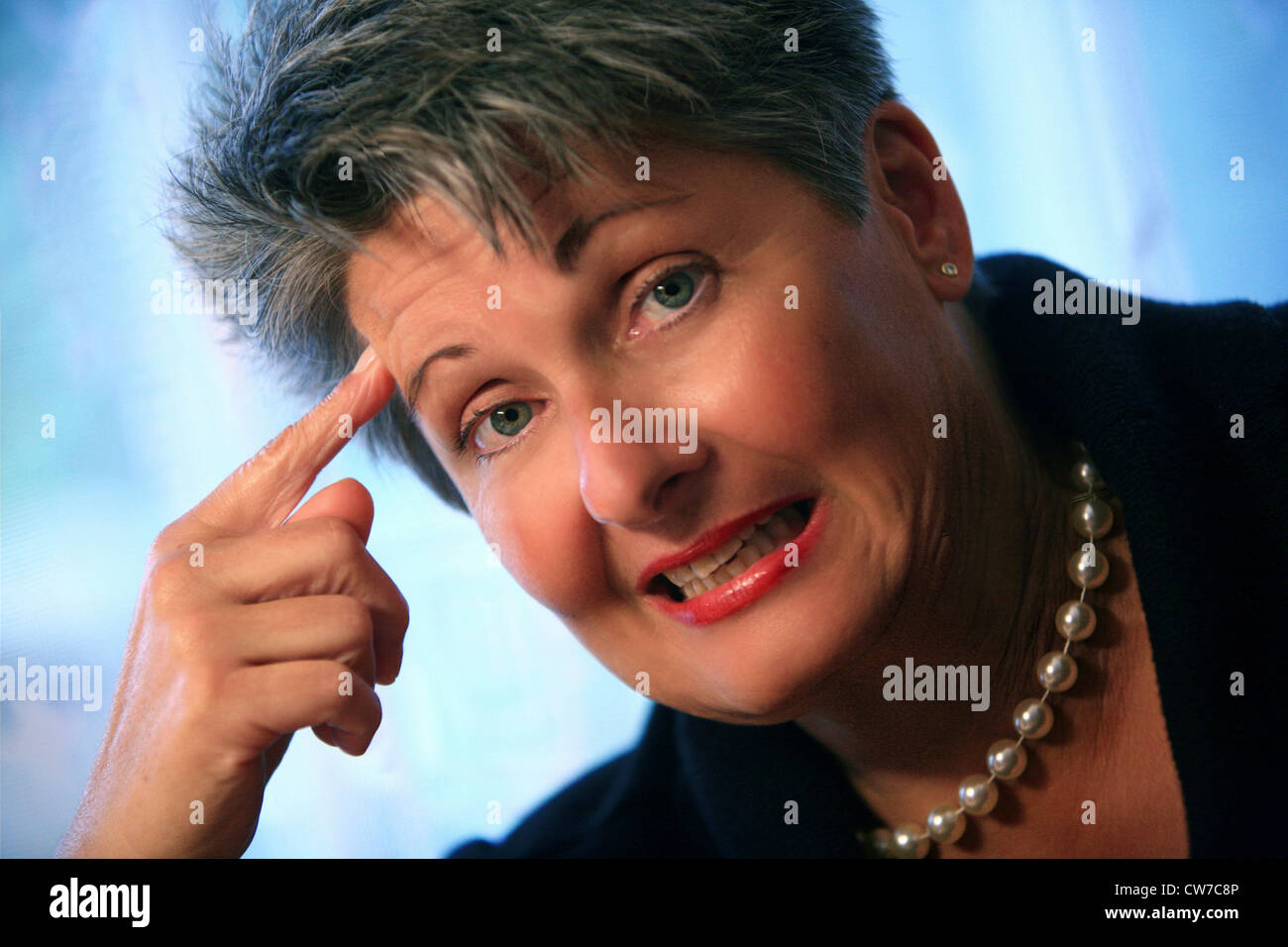 portrait of a grey-haired woman tapping her forehead at the viewer ...