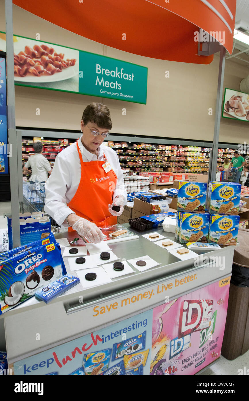 White female senior citizen employee works at a food sample kiosk at a ...