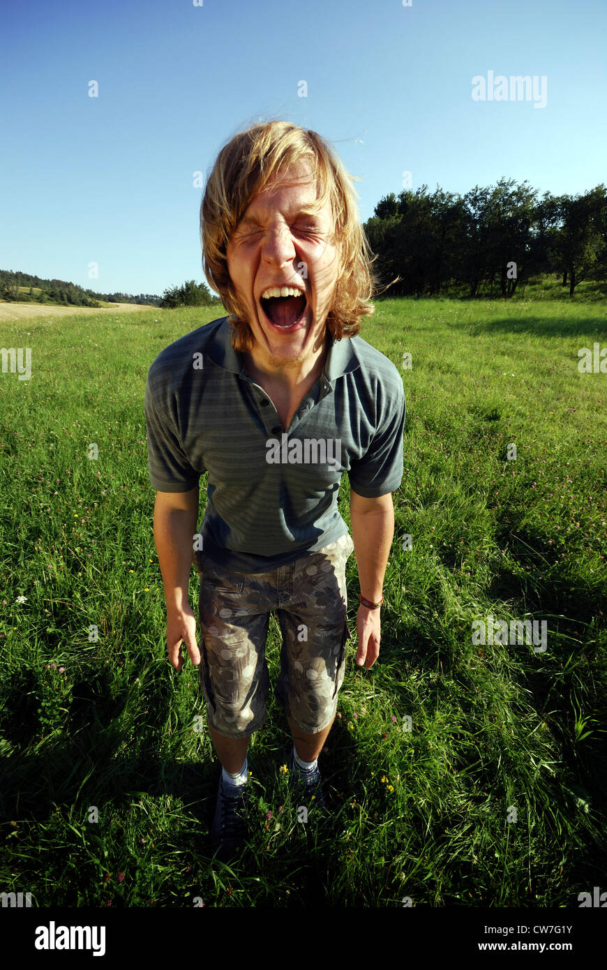 young man standing on a meadow, screaming Stock Photo - Alamy