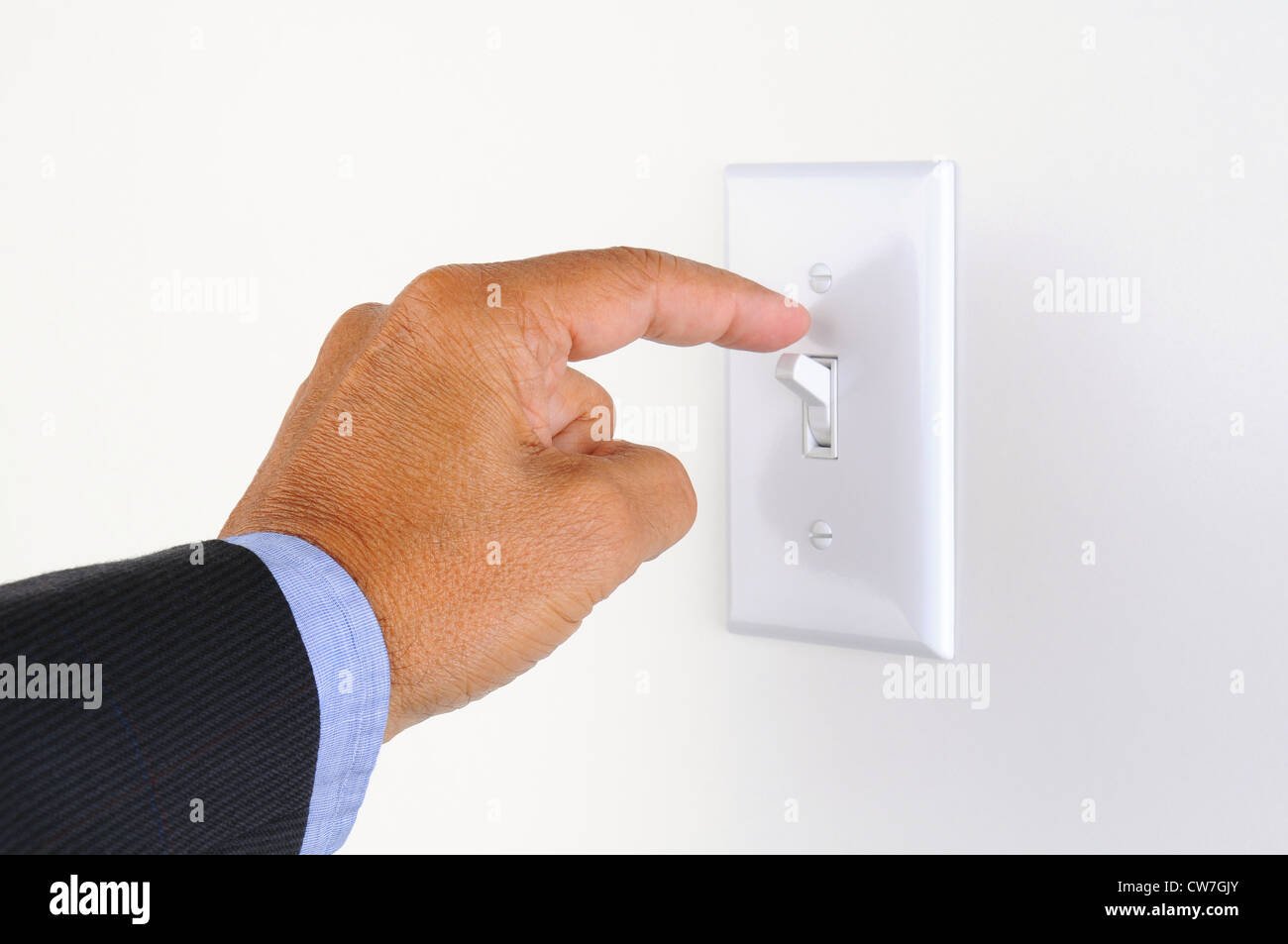 Man's hand with finger on light switch, about to turn off the lights ...
