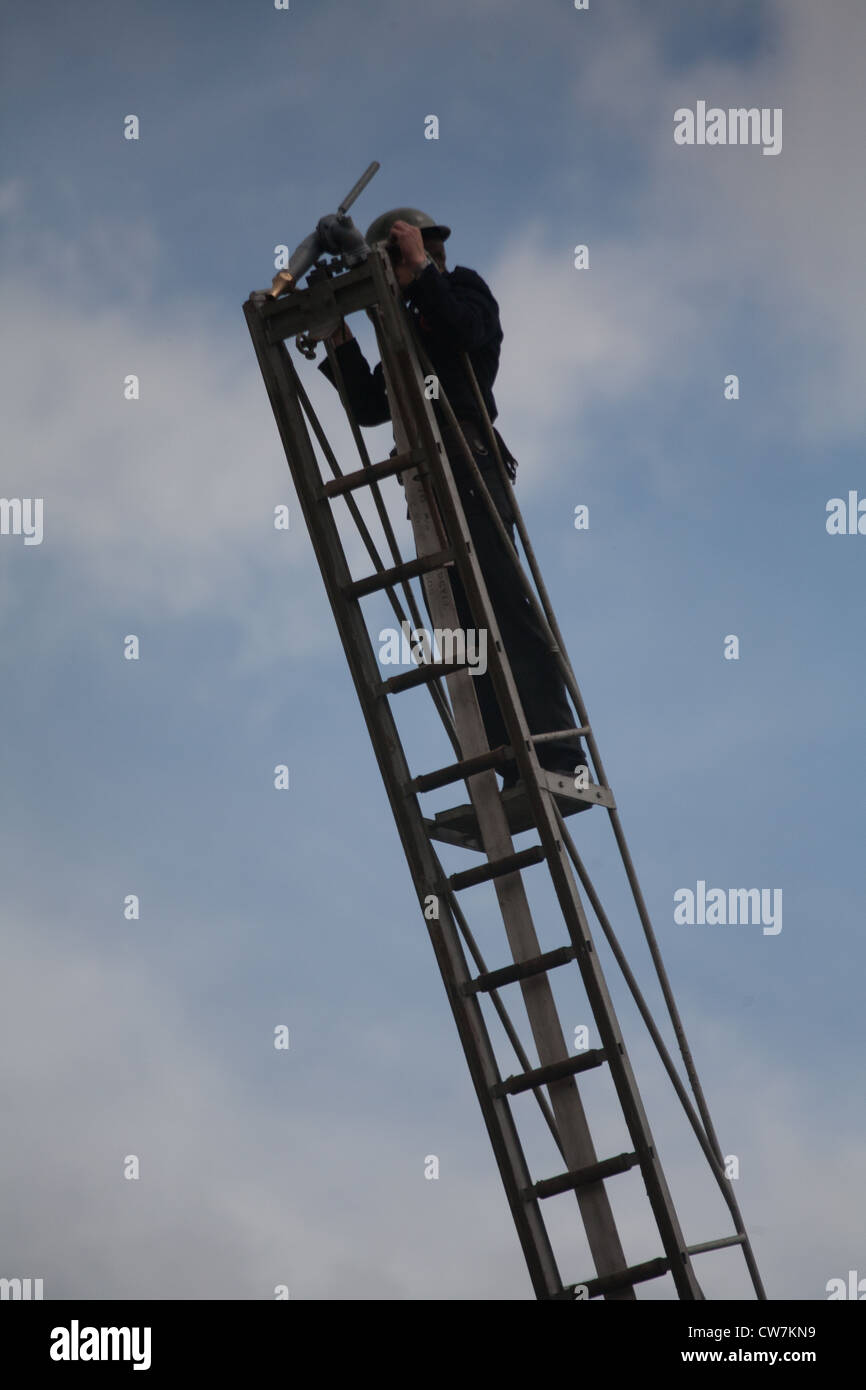 Member of the 1940's National Fire Service on ladder with water jet ...