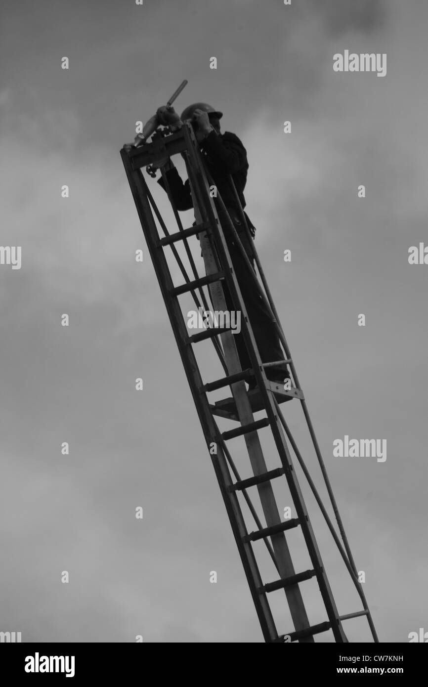 Member of the 1940's National Fire Service on ladder with water jet ...