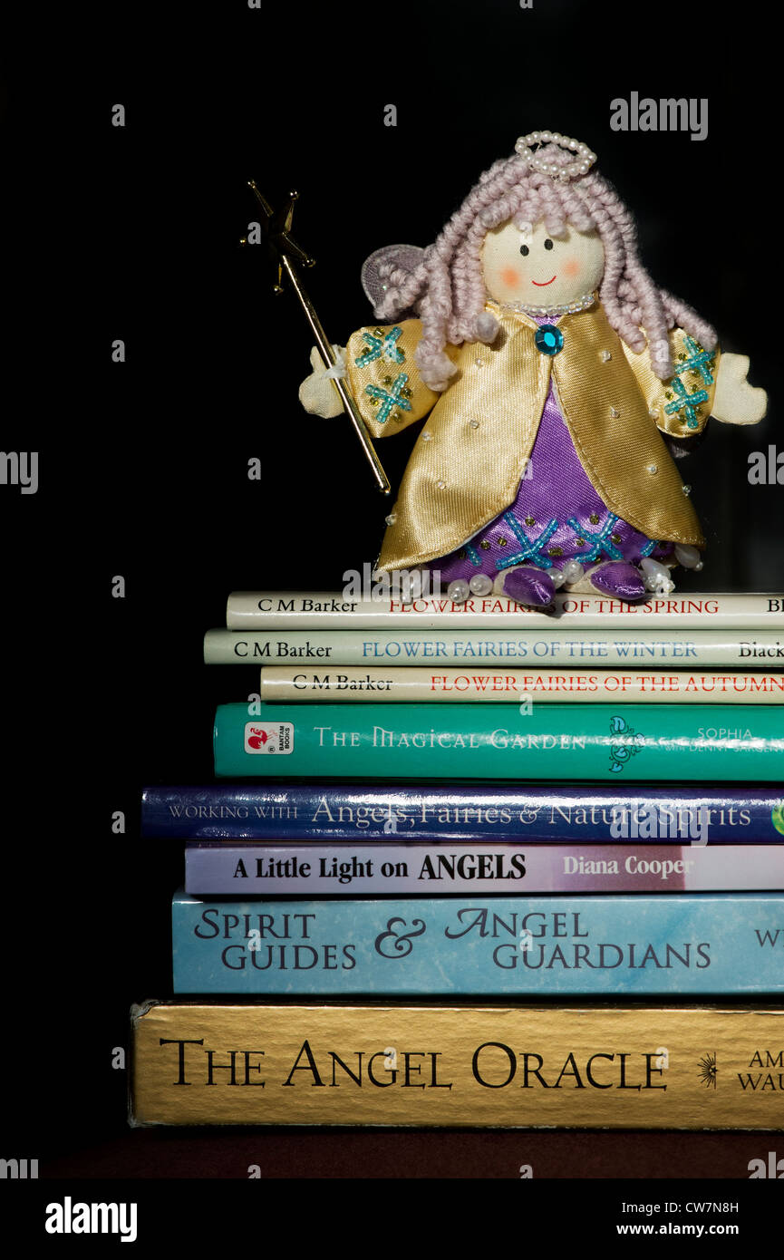 Childs Angel doll sitting on spiritual angel books lit by sunlight ...