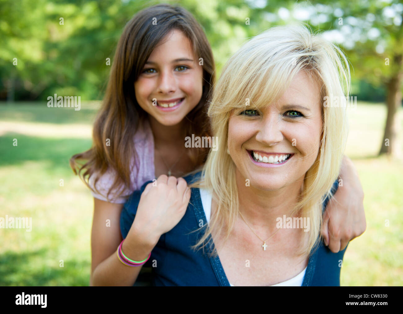 Young daughter on her mother's back outside smiling Stock Photo - Alamy