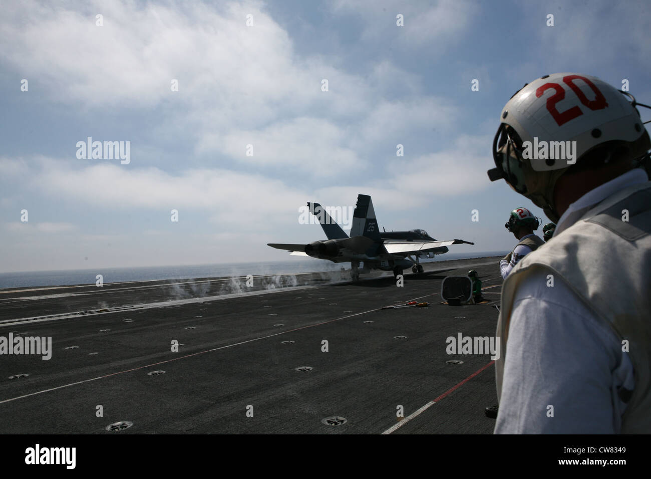 Marines and sailors look on as an F/A-18 Hornet is launched from a ...