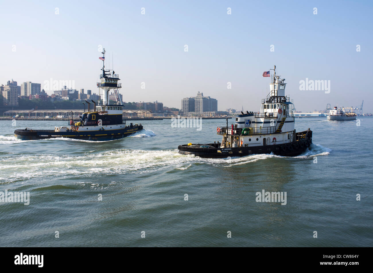 Tug boats and a tanker head downstream on the East River, New York ...