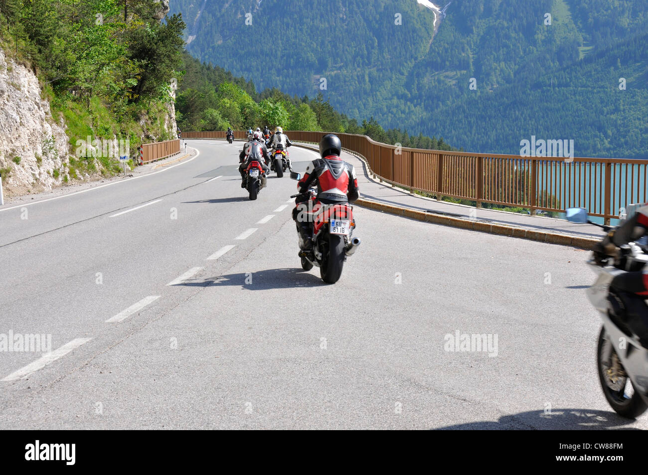 People driving sport motorcycles in The Alps mountains, going uphill ...