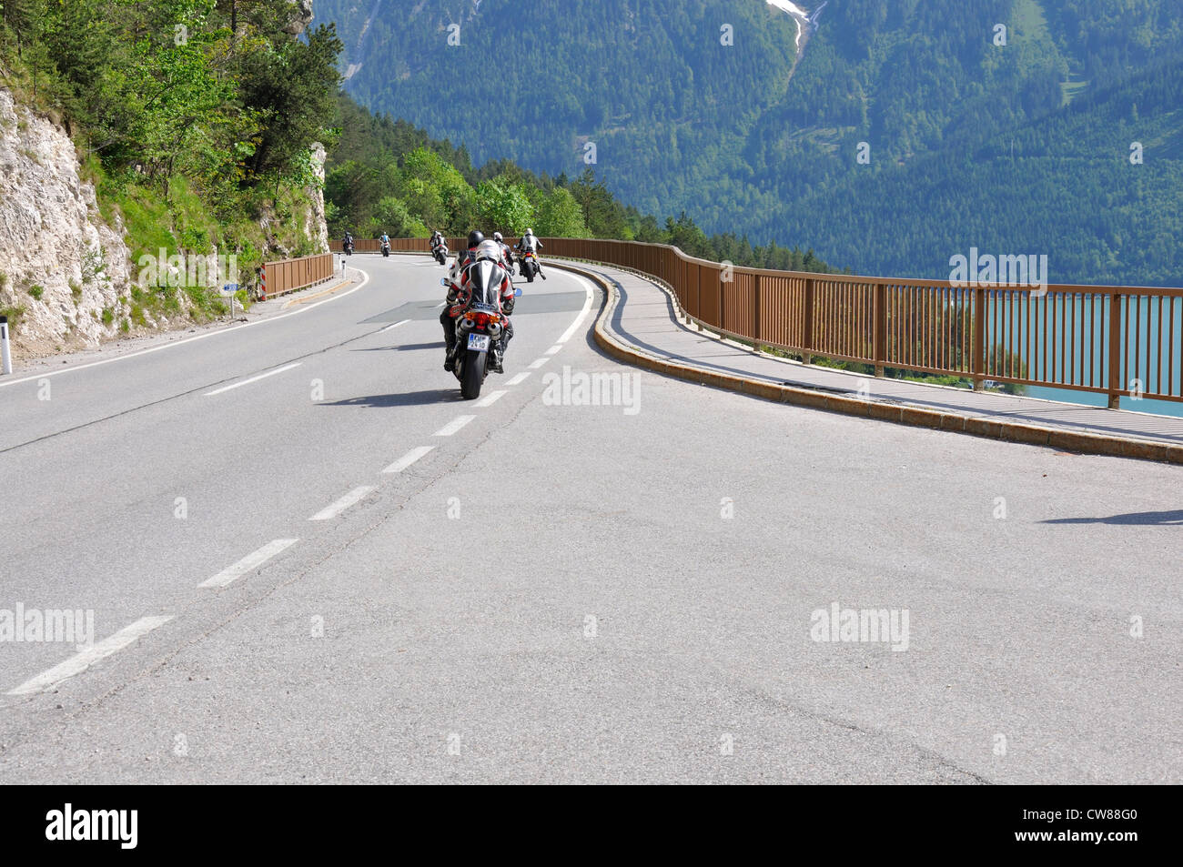 People driving sport motorcycles in The Alps mountains, going uphill ...