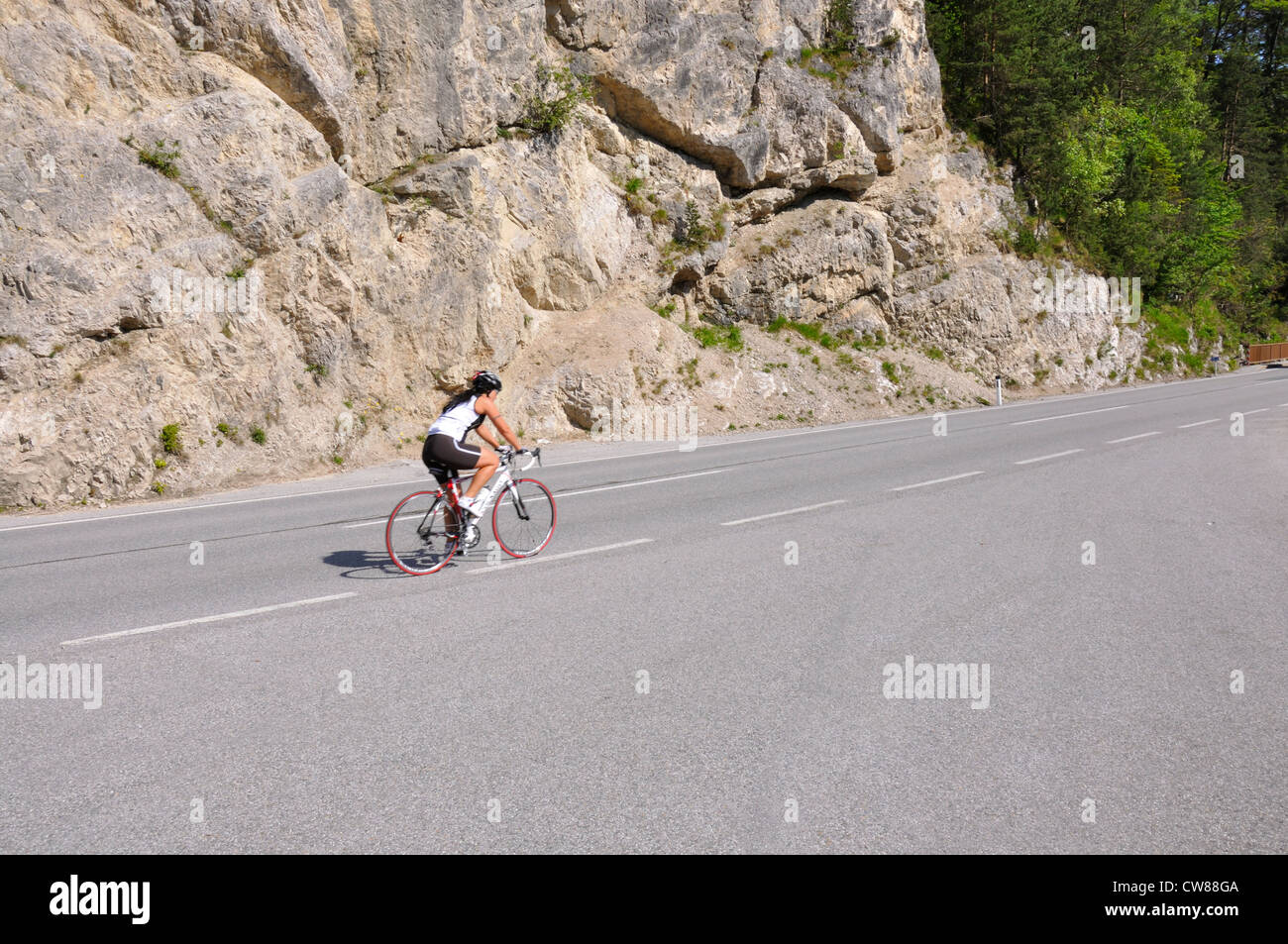 Woman riding bicycle uphill in mountain road Stock Photo - Alamy