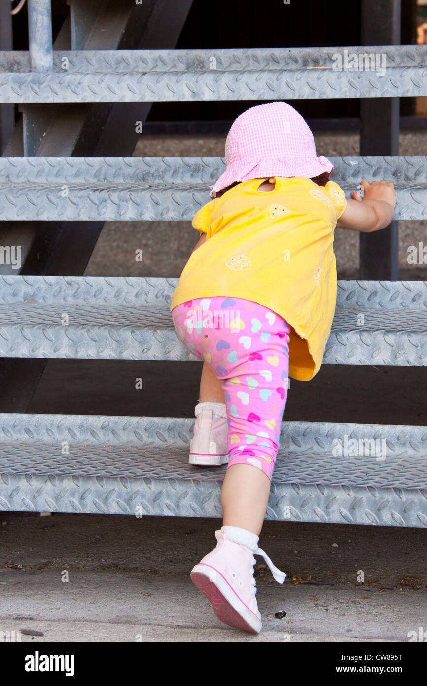 Little girl trying to escalate some metal stairs Stock Photo - Alamy