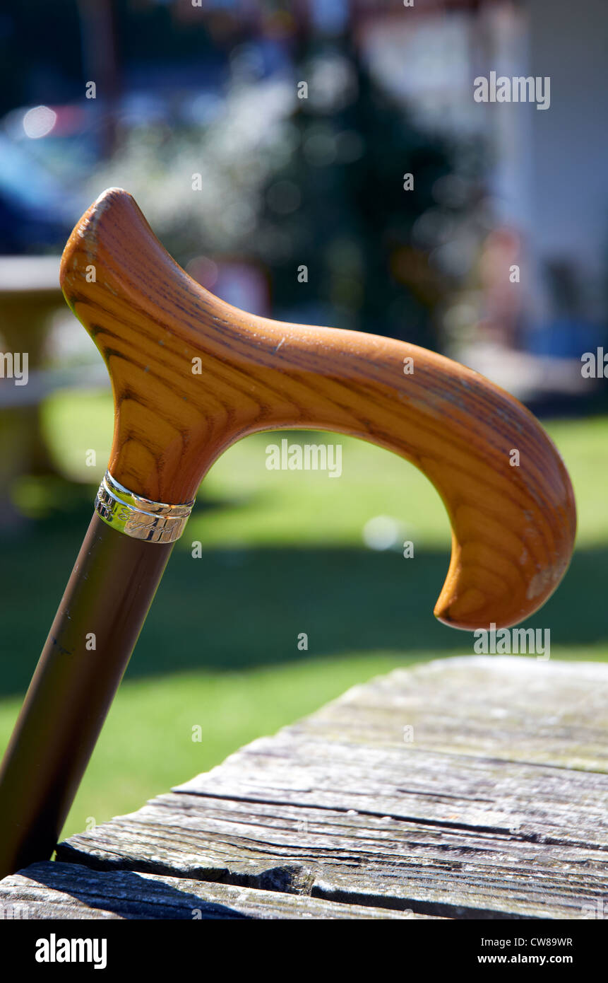 Metal walking stick with wooden handle leaning against a wooden table ...