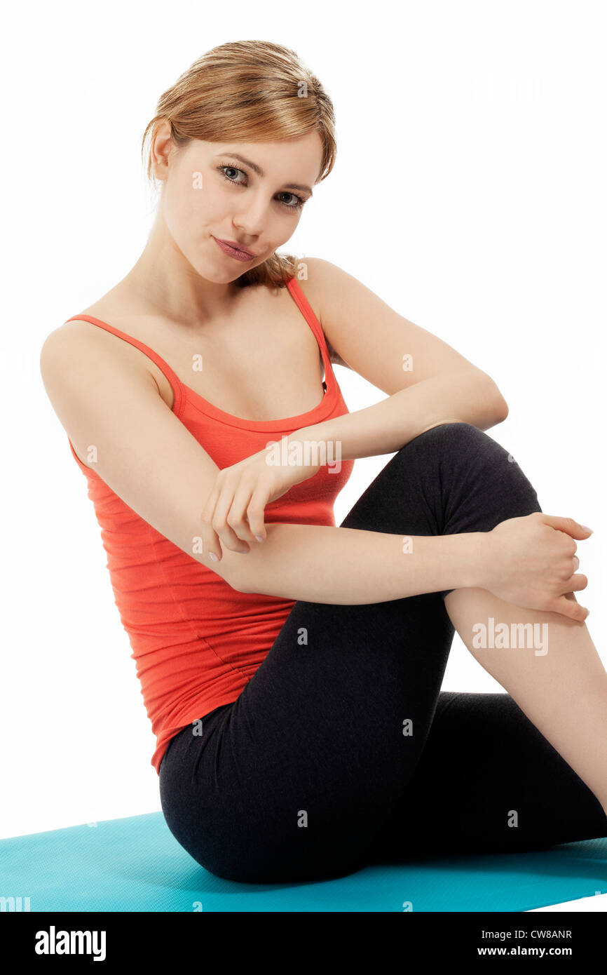 young fitness woman making a pause sitting on a blue mat on white ...