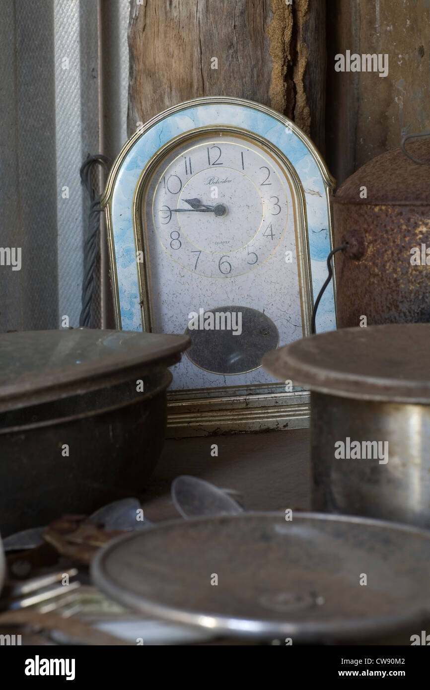Old clock frozen in time in a derelict shack amongst kitchen utensils ...