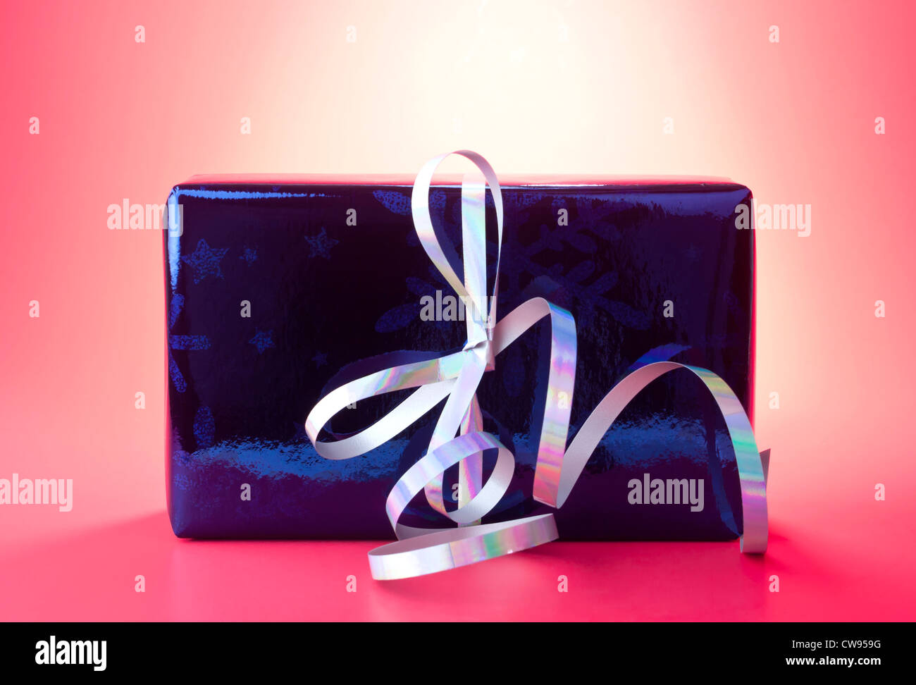 Present or gift wrapped in blue shiny wrapping paper with silver curly ...