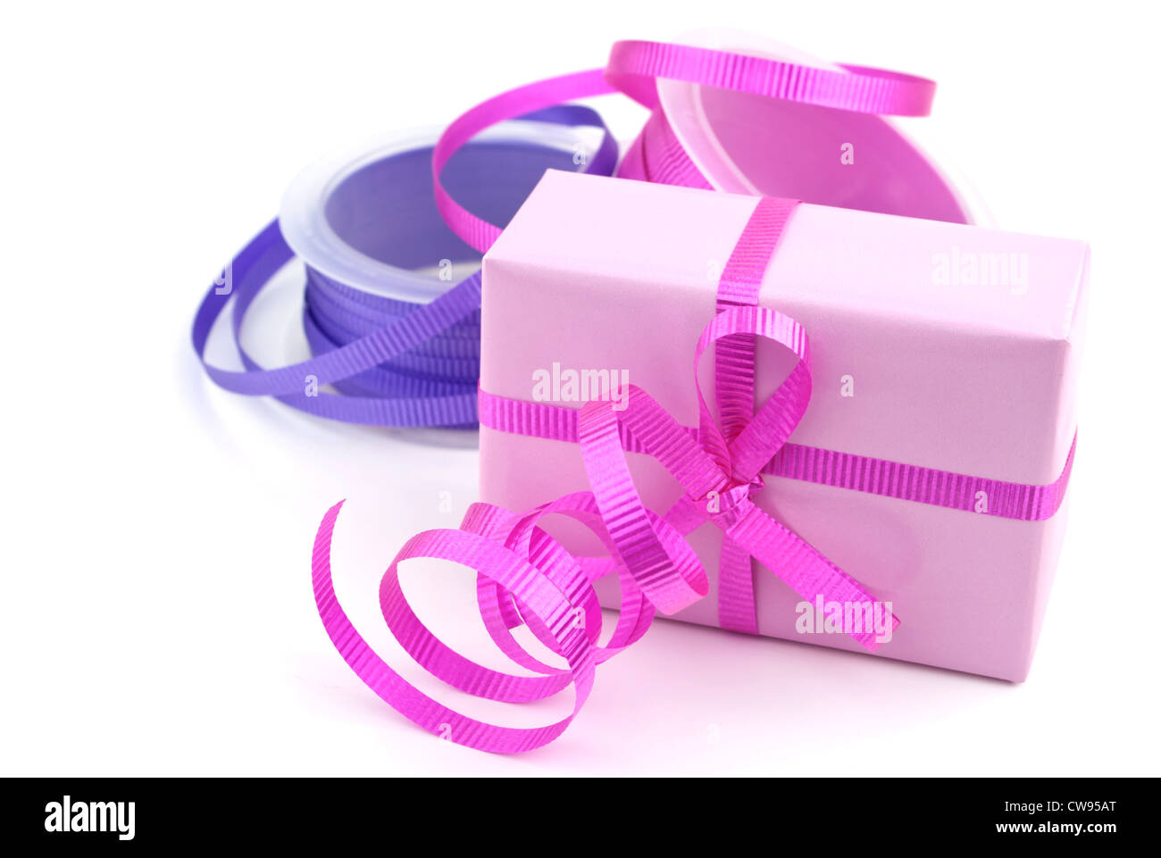Gift box wrapped in pink wrapping paper and purple curly ribbon ...