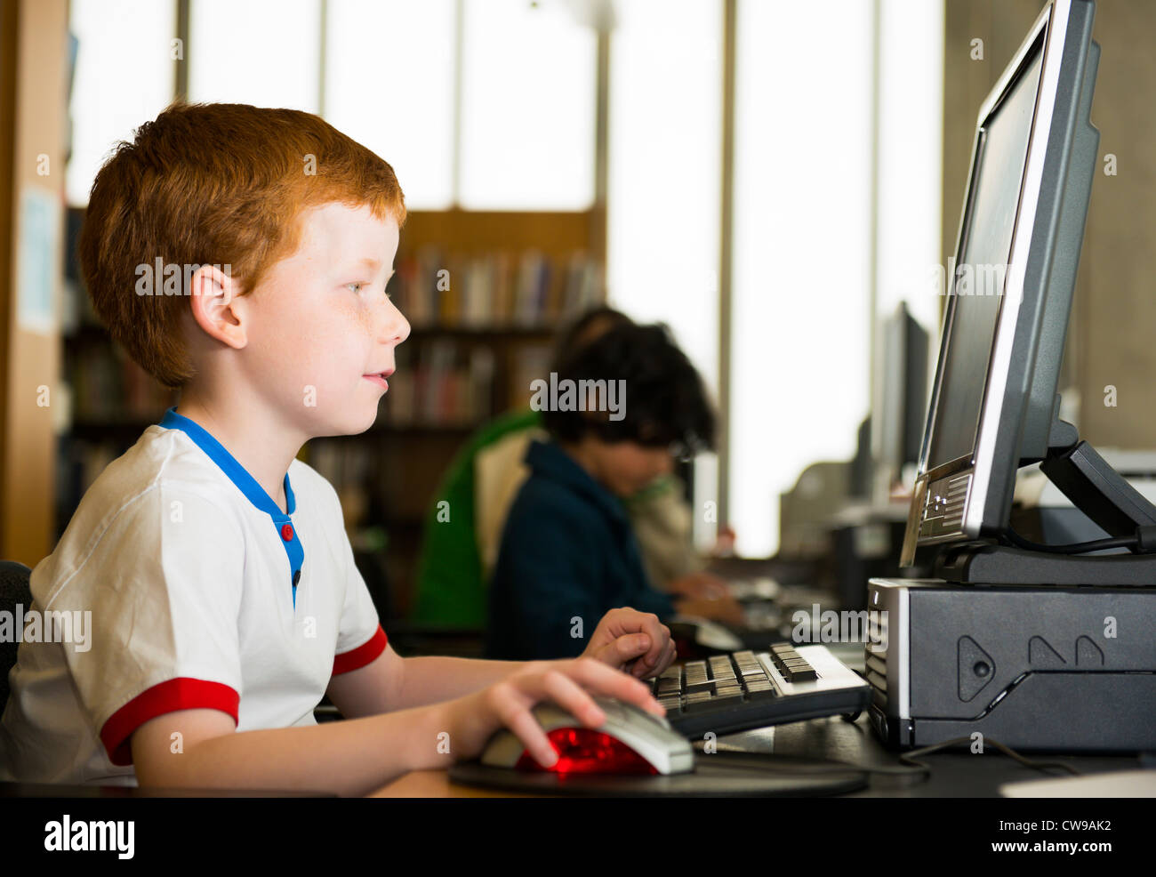 Child in library, working on a computer Stock Photo - Alamy