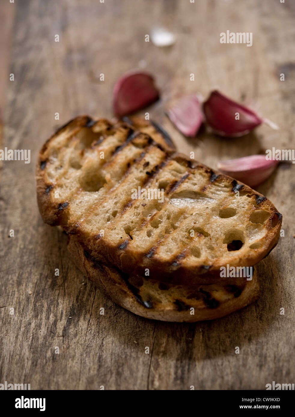 Toasted Ciabatta bread with cloves of garlic on wooden board Stock ...