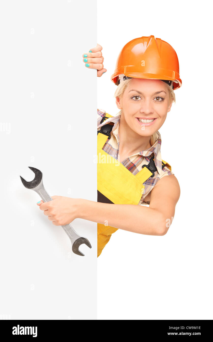 Female construction worker holding a wrench, standing behind white ...