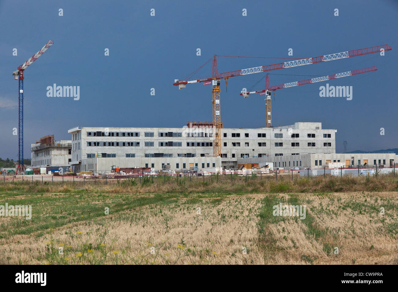 A large building site with three tall cranes in the suburban landscape ...