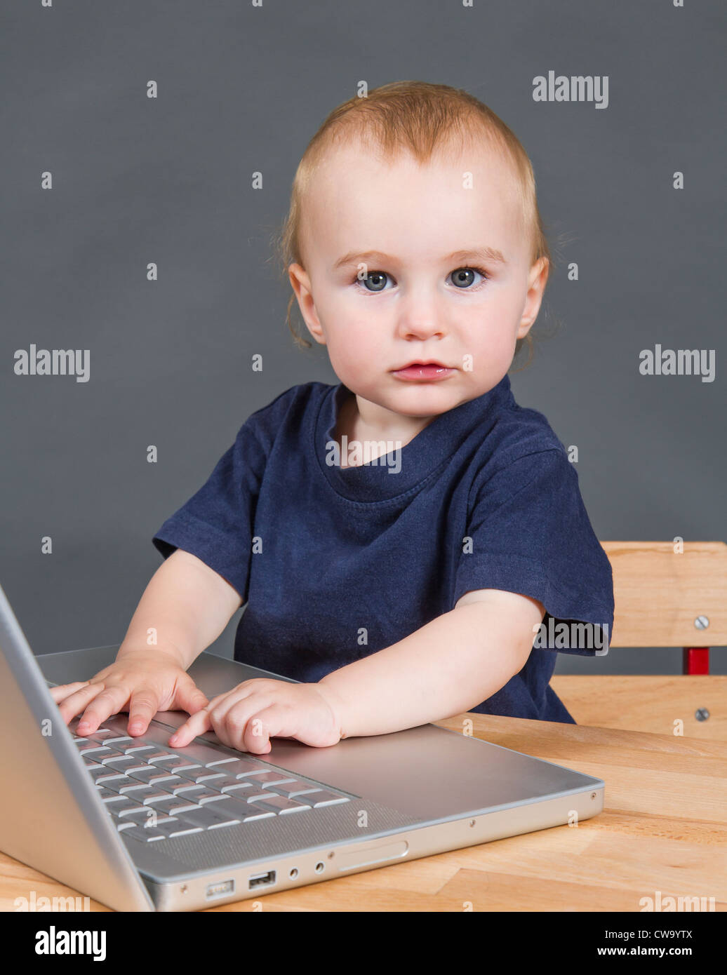 young child with laptop computer on wooden desk in grey background ...