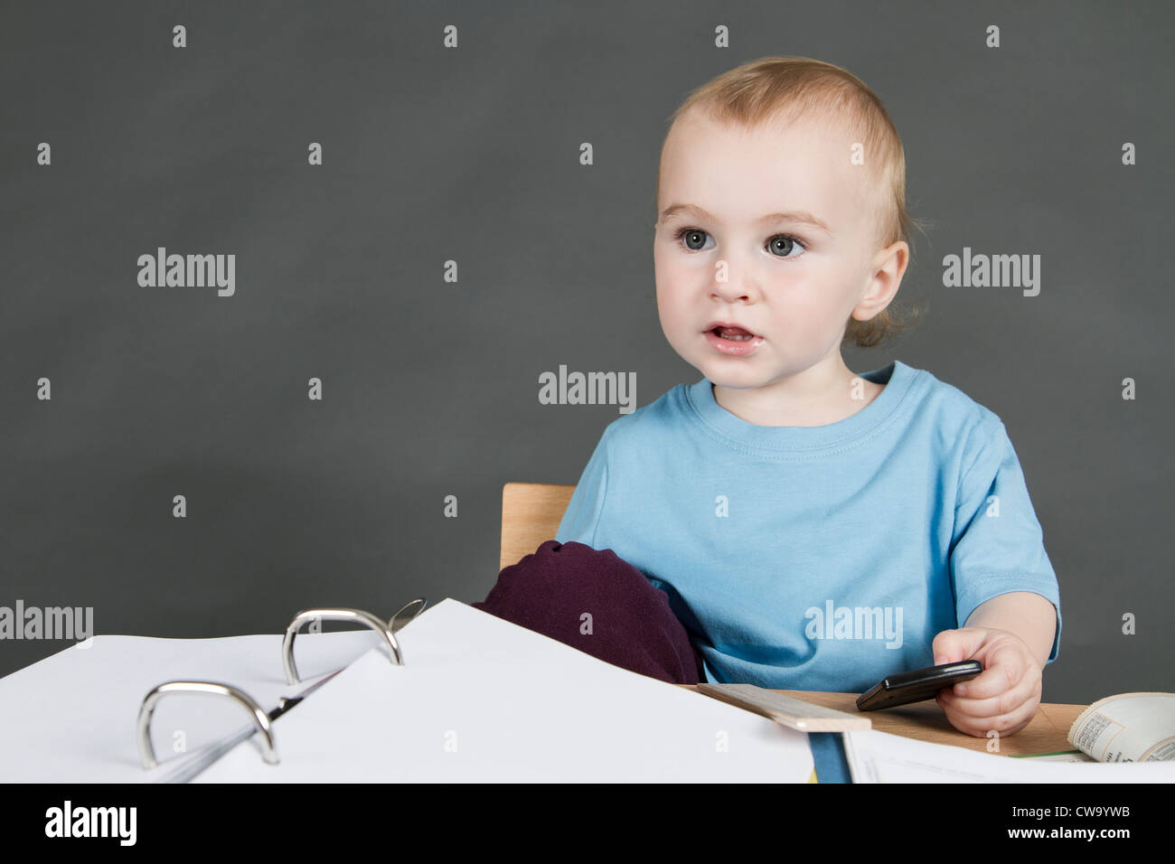 young child at small desk in grey background Stock Photo - Alamy